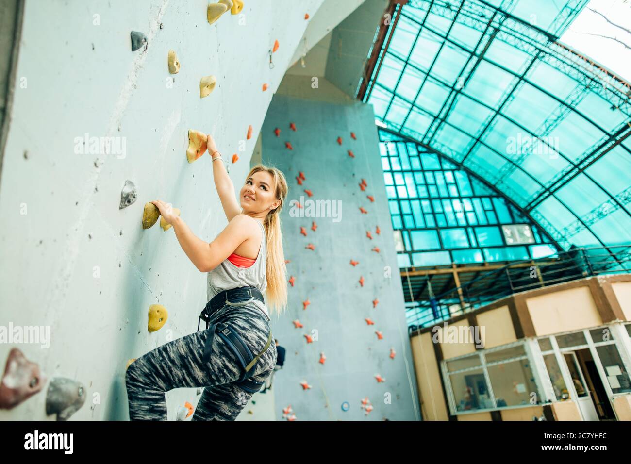 Beautiful young woman starts to climbing big artificial wall Stock ...
