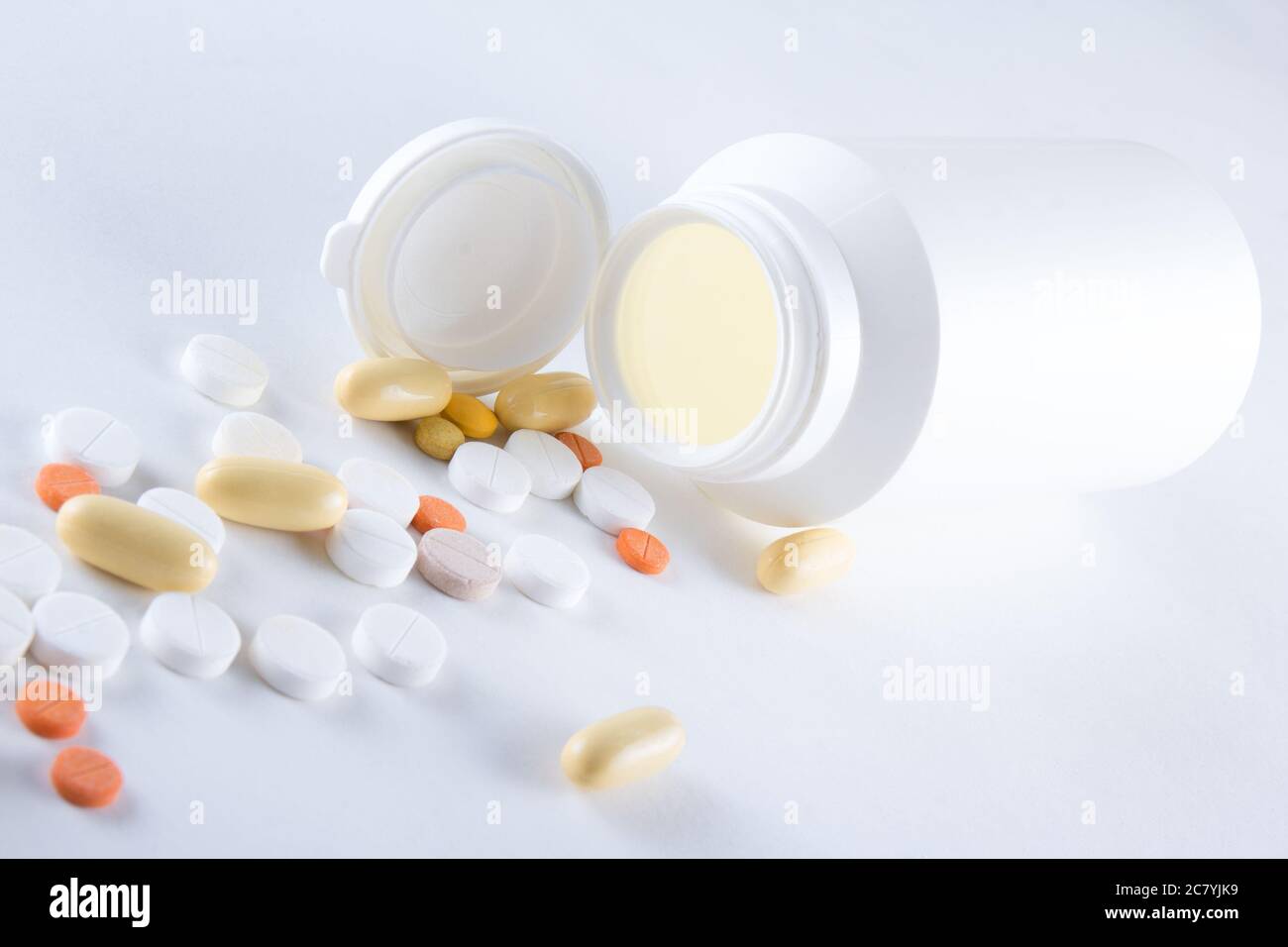 close up of colorful capsules pouring from plastic bottle over white ...