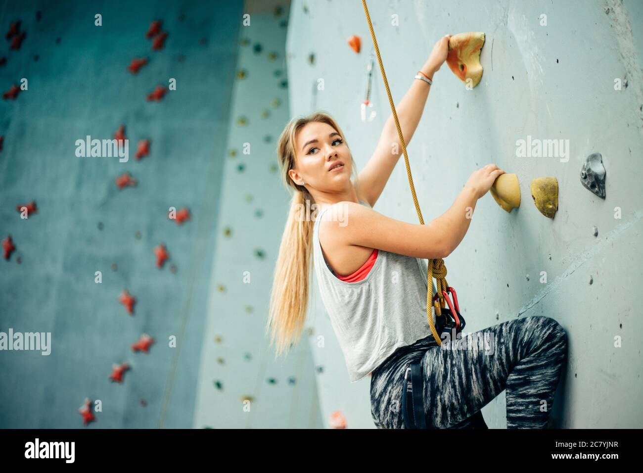 Young woman practicing rock-climbing on a rock wall indoors Stock Photo ...