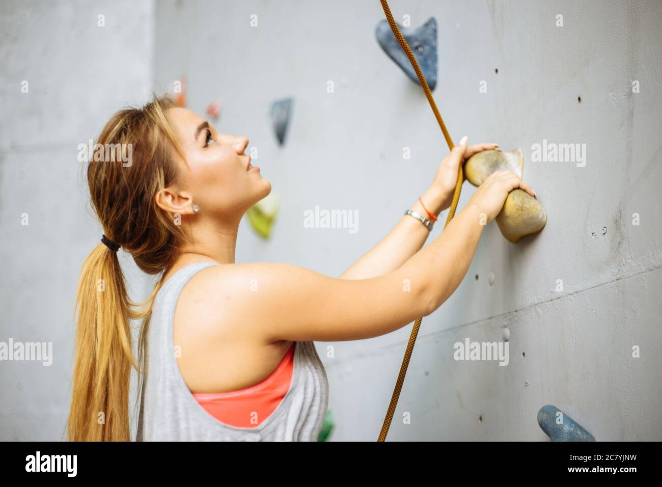 Beautiful young woman starts to climbing big artificial wall Stock ...