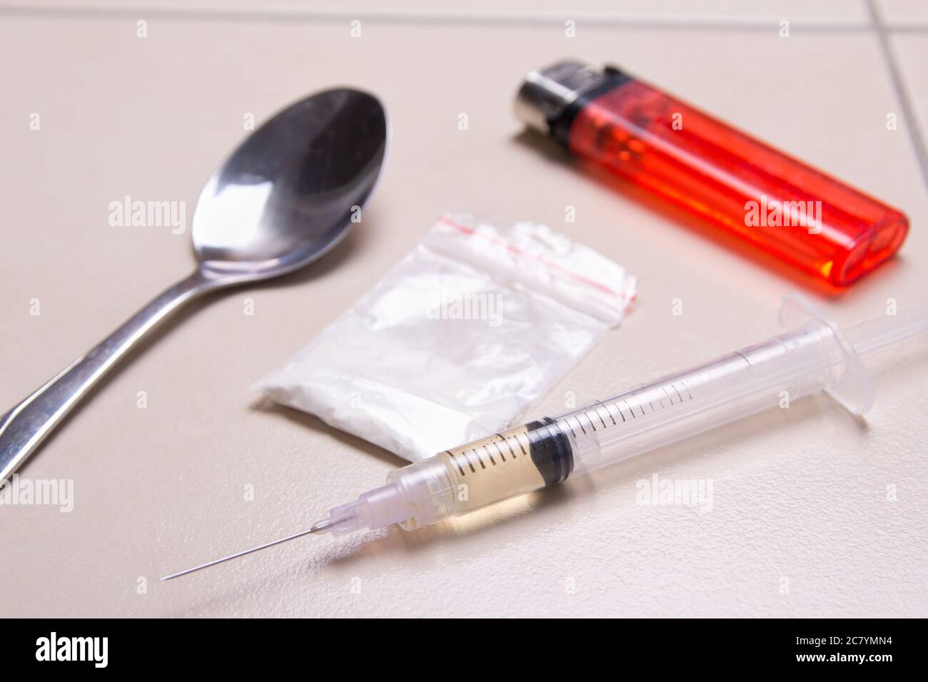 close up of drug syringe, heroin powder, spoon and lighter on tiled ...
