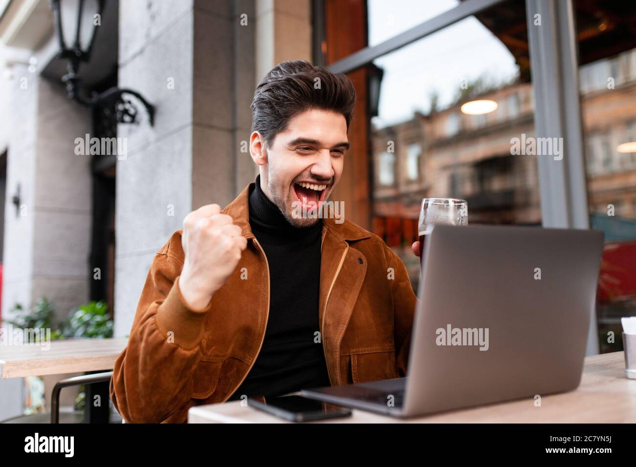 Young positive casual man happily showing yes gesture while working on ...