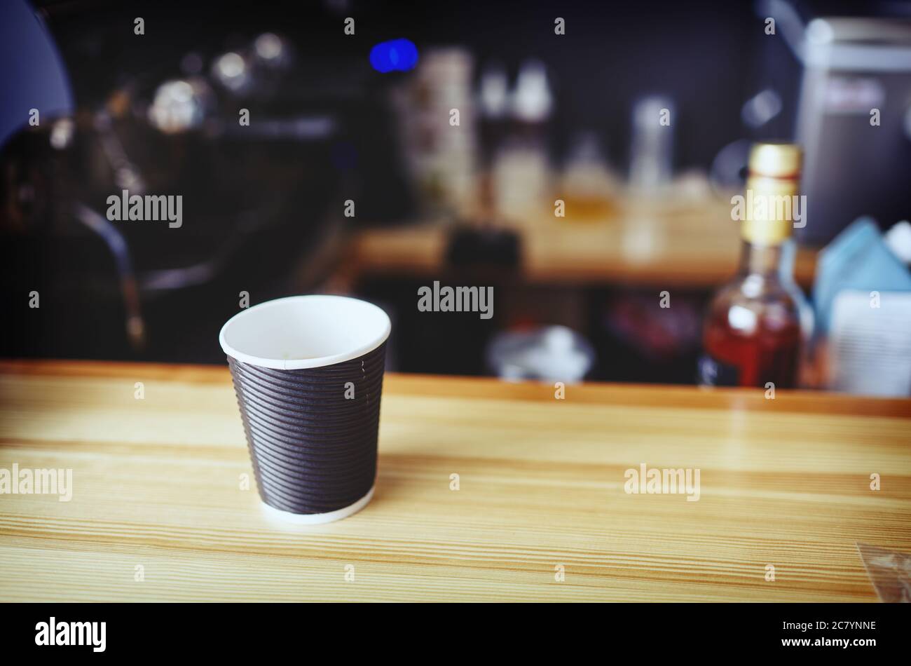 Disposable coffee paper cup on bar counter. Morning light falls from ...