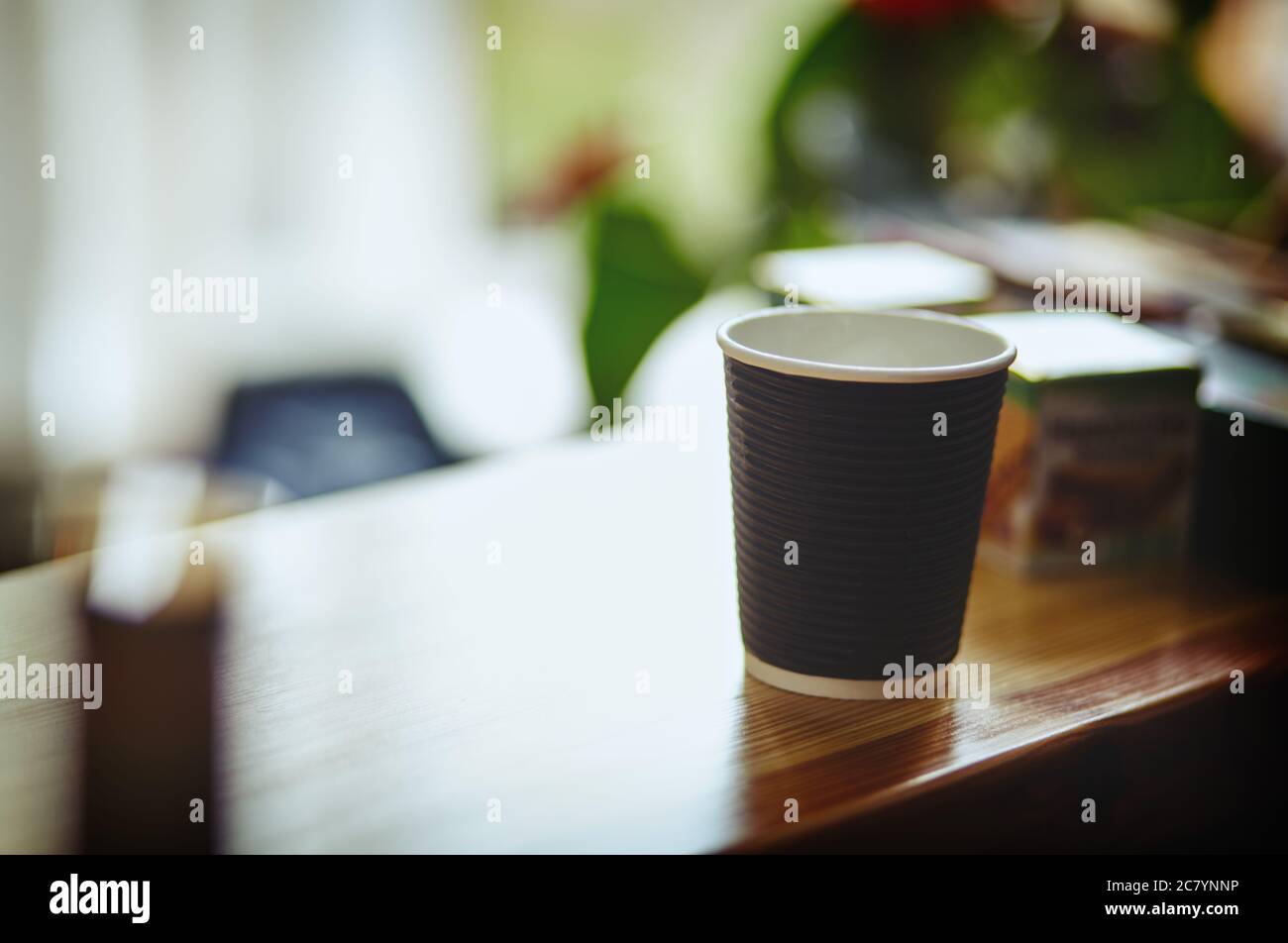 Disposable coffee paper cup on bar counter. Morning light falls from ...