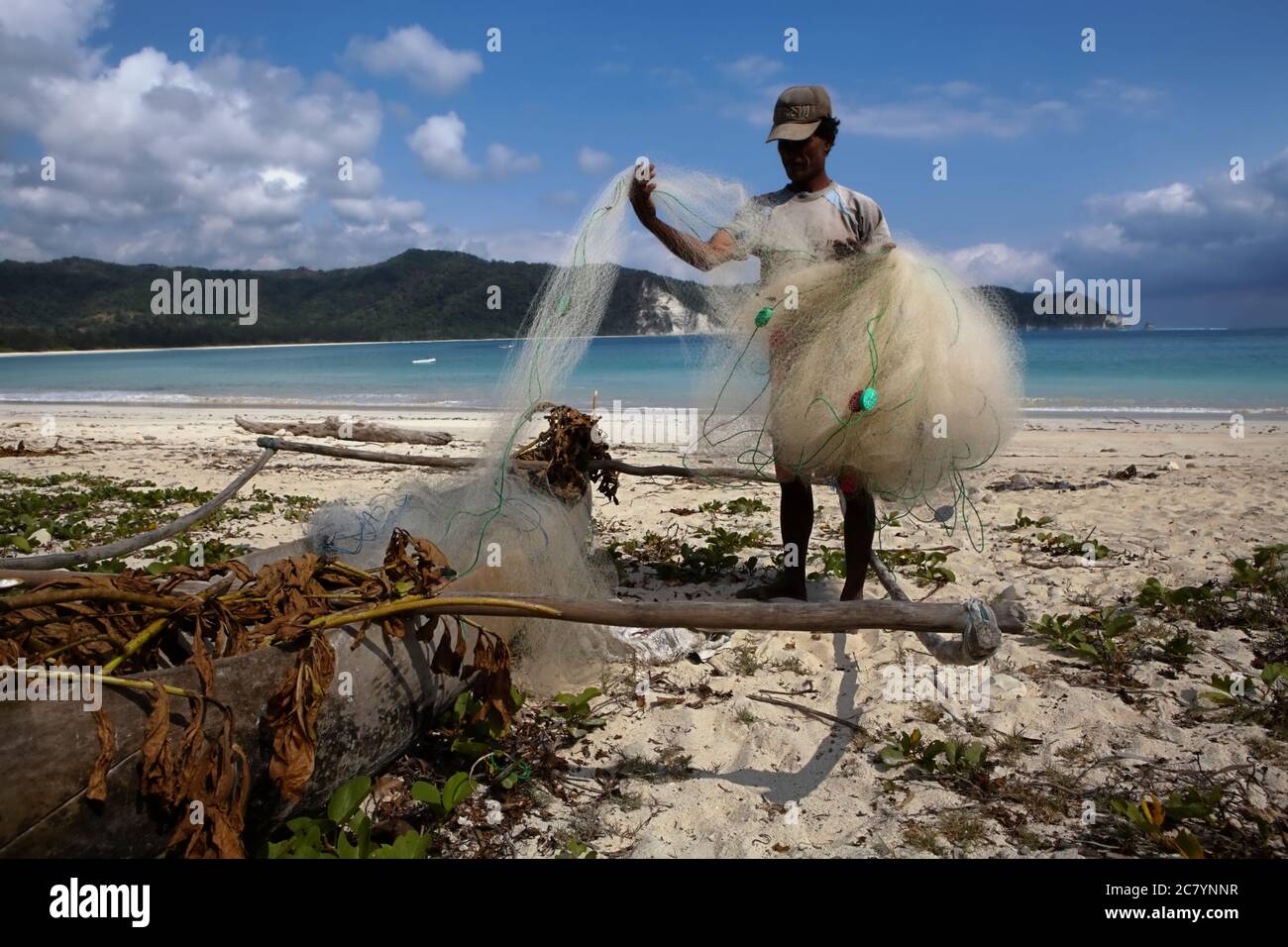 A subsistence fisherman unrolling his fishing net on the beach of ...