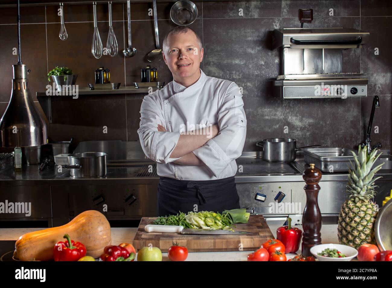 Chef leaning on the counter with a dish in a commercial kitchen Stock ...