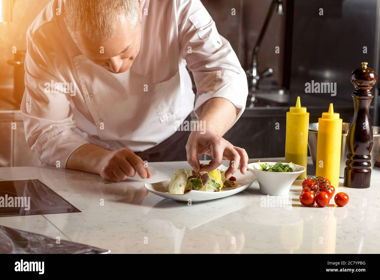 Chef sprinkling spices on dish in commercial kitchen Stock Photo - Alamy