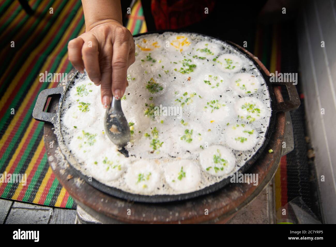 Hand and spoon picking Kanom Krok or Kind of Thai sweetmeat, Thai ...