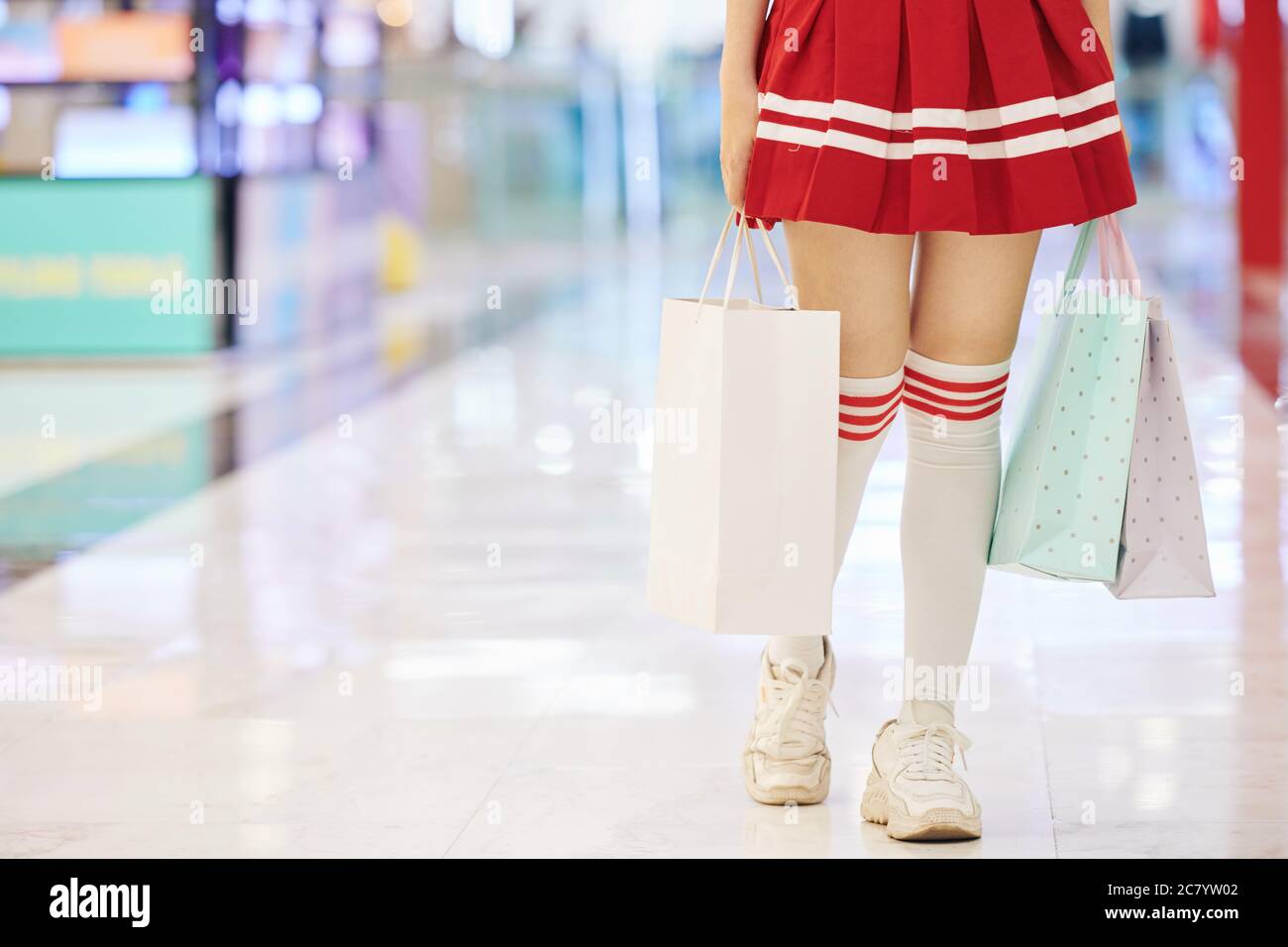 Cropped image of girl in thigh high socks walking with shopping mall ...
