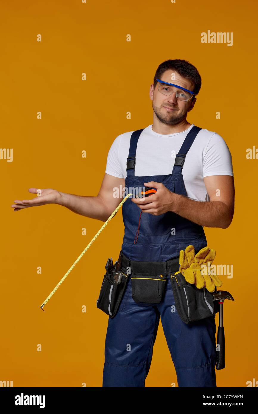 confused caucasian repairman worker in uniform holding measure tape and ...