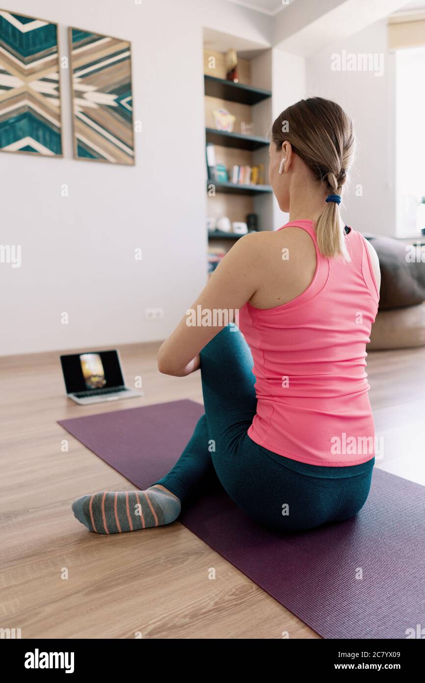 Back view authentic woman practicing yoga at home using online training ...