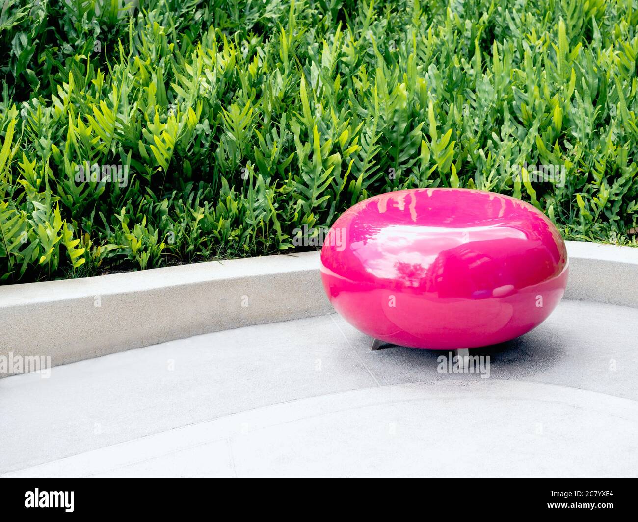 Modern bright pink colors round chair on the ground on green garden ...