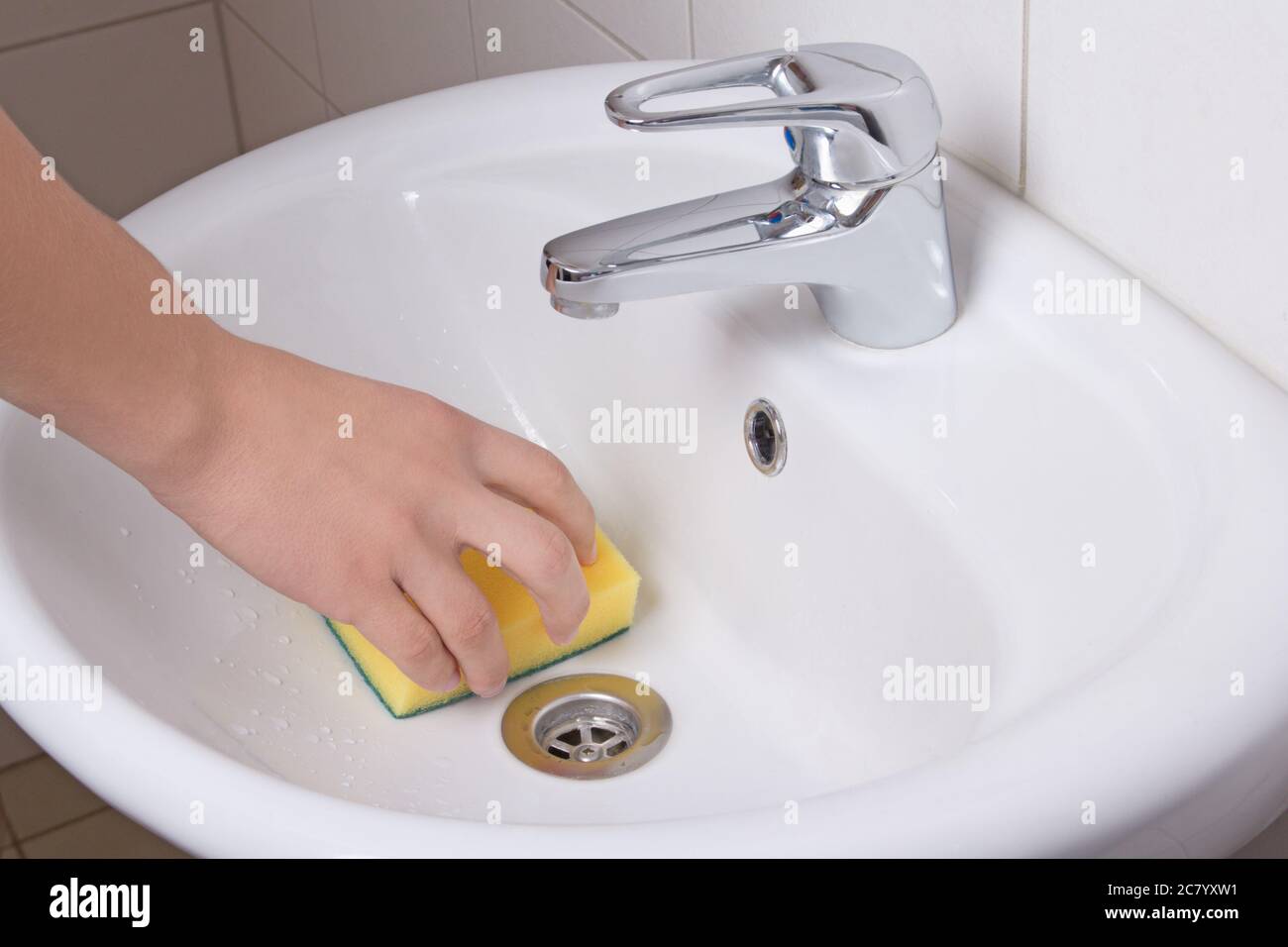 Hand with sponge cleaning sink Stock Photo - Alamy