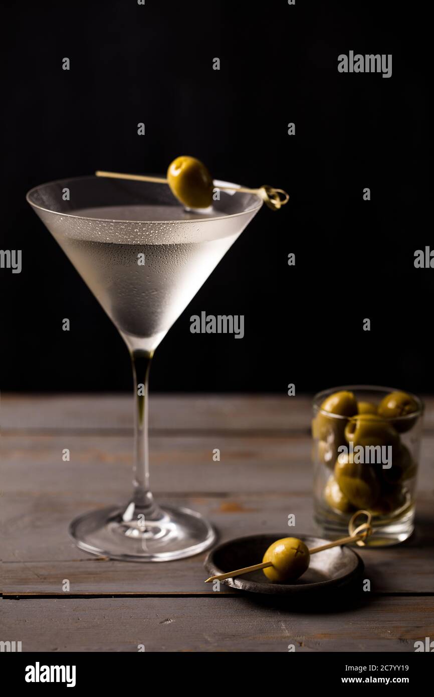 Chilled martini cocktail served with an olive set on a grey wooden bar ...