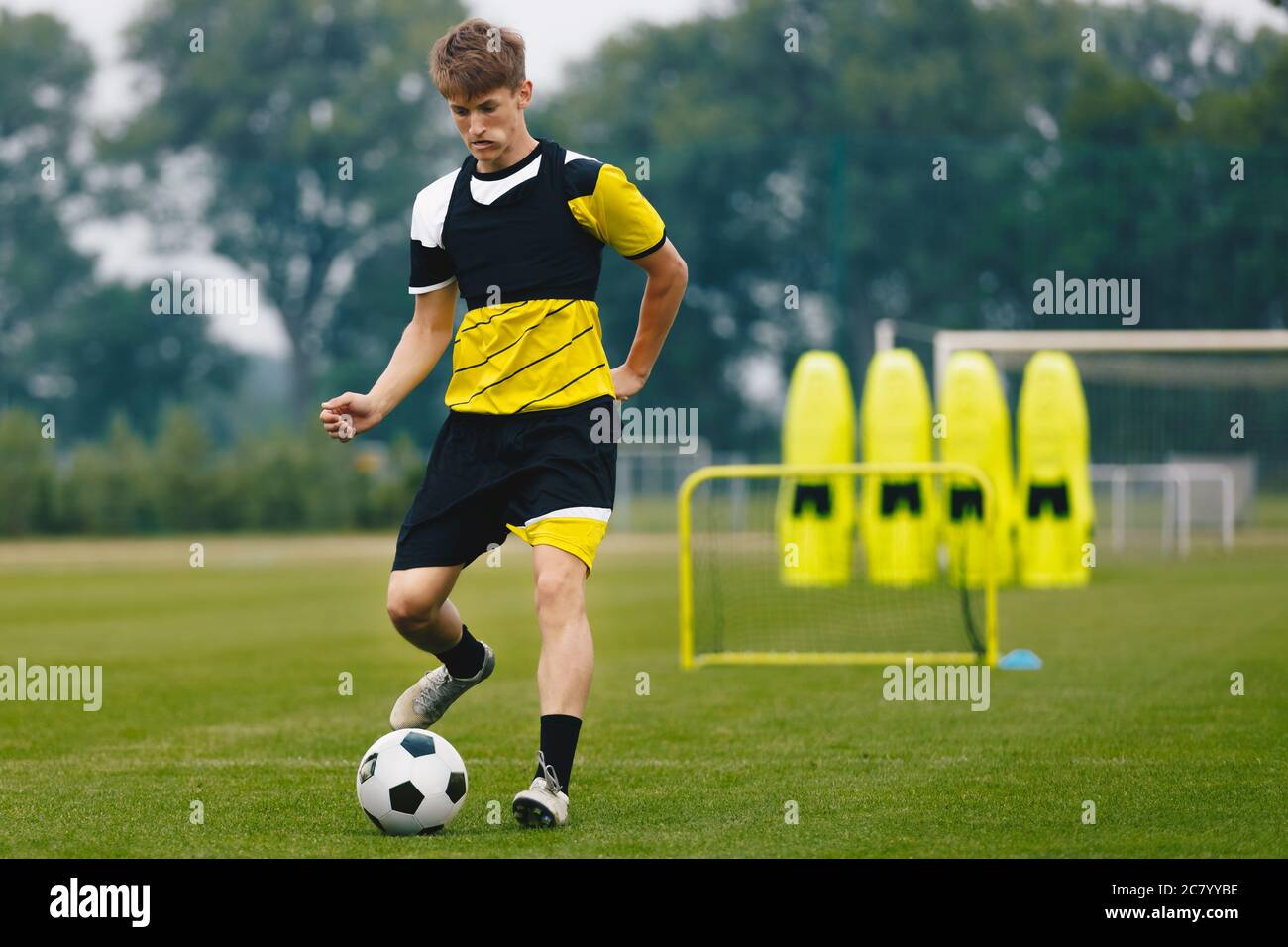 Young teenage soccer player on training field kicking soccer ball ...
