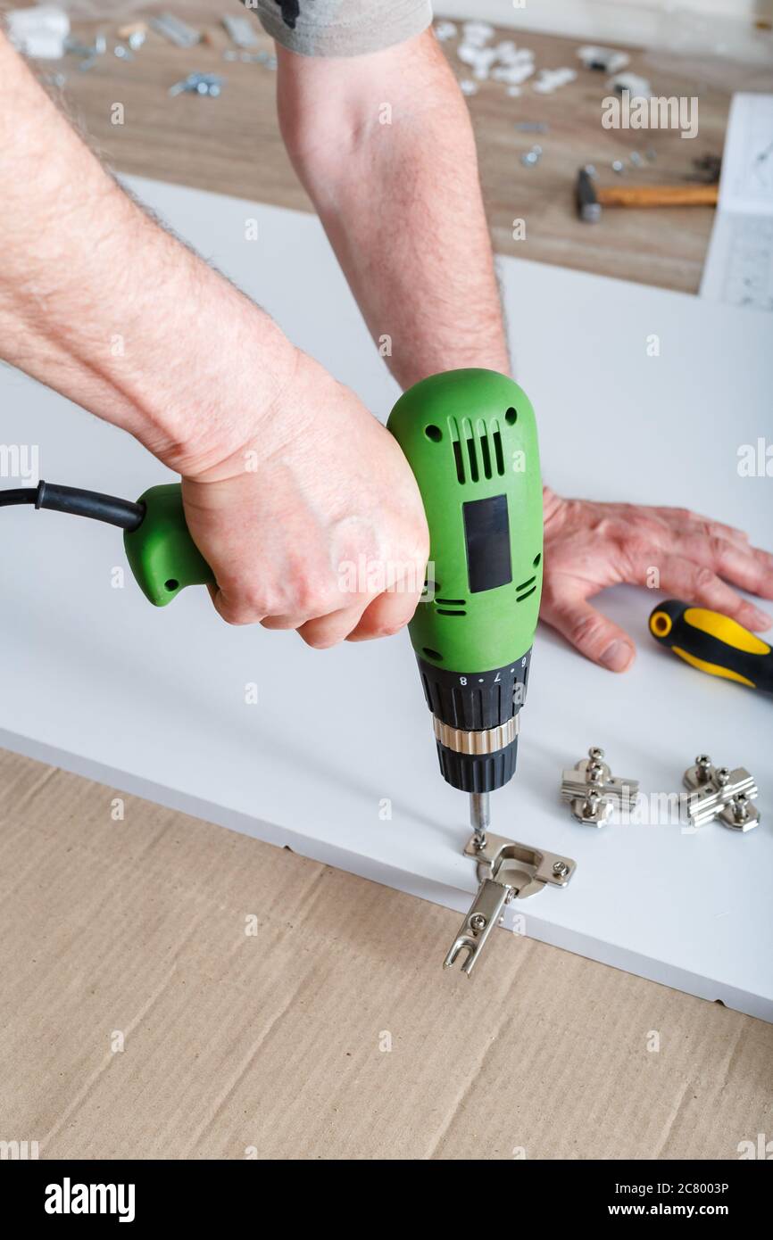 Furniture assembly using drill. Male hands master collects furniture ...