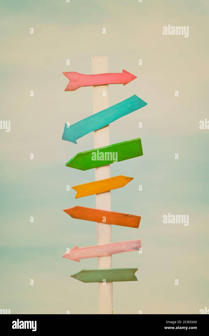 Colorful wooden direction arrow signs on a wooden pole Stock Photo - Alamy