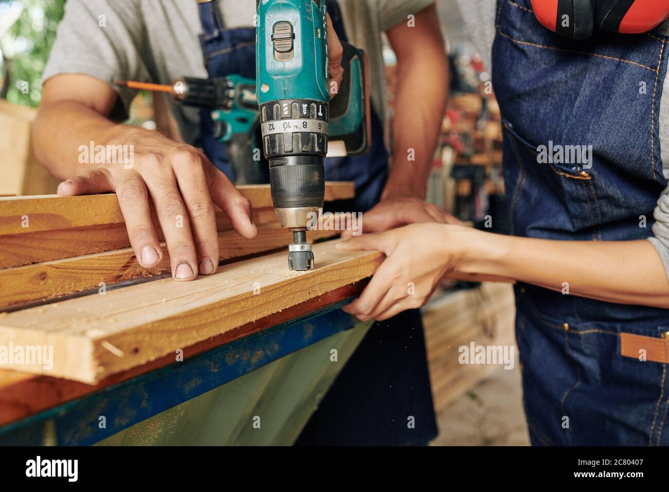 Close-up image of carpenter helping to hold wooden plank when his ...