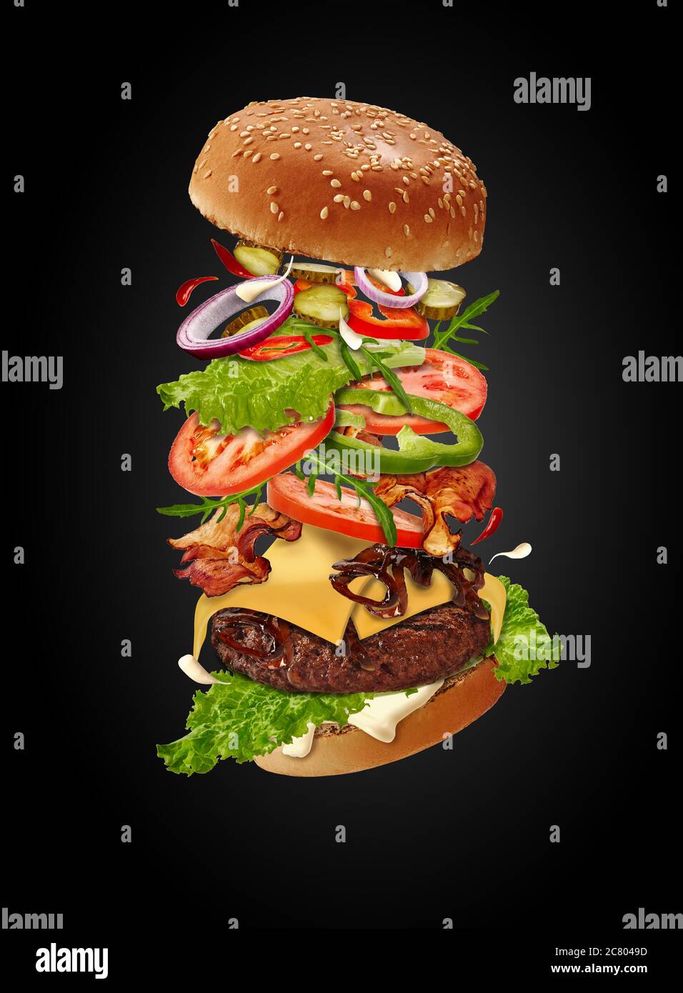 Maxi burger with flying ingredients against black background. Ham, beef ...