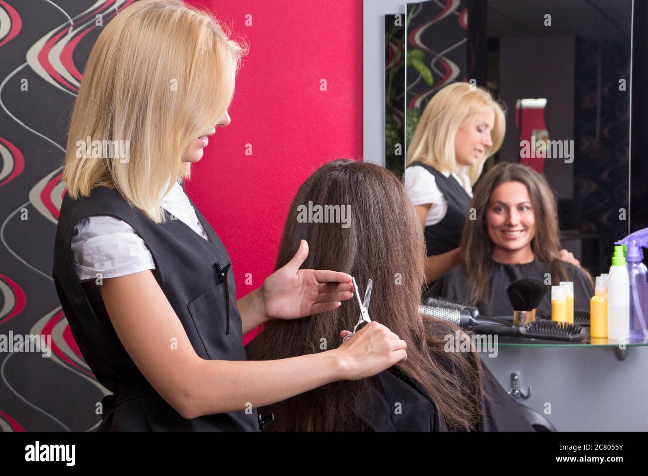 female hairdresser makes hairstyle for beautiful girl in beauty salon ...