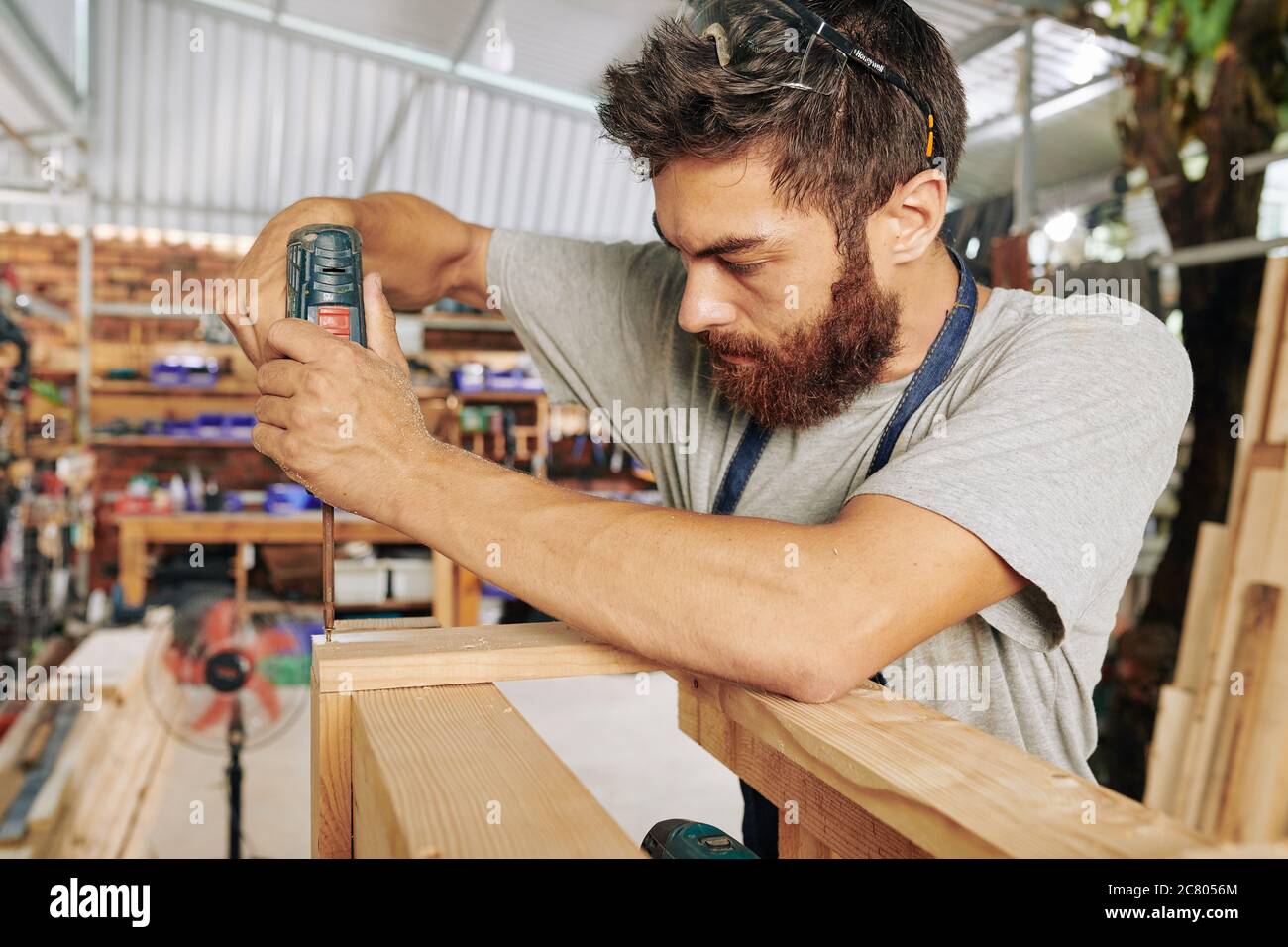 Serious carpenter assembling wooden stand in his studio, making ...