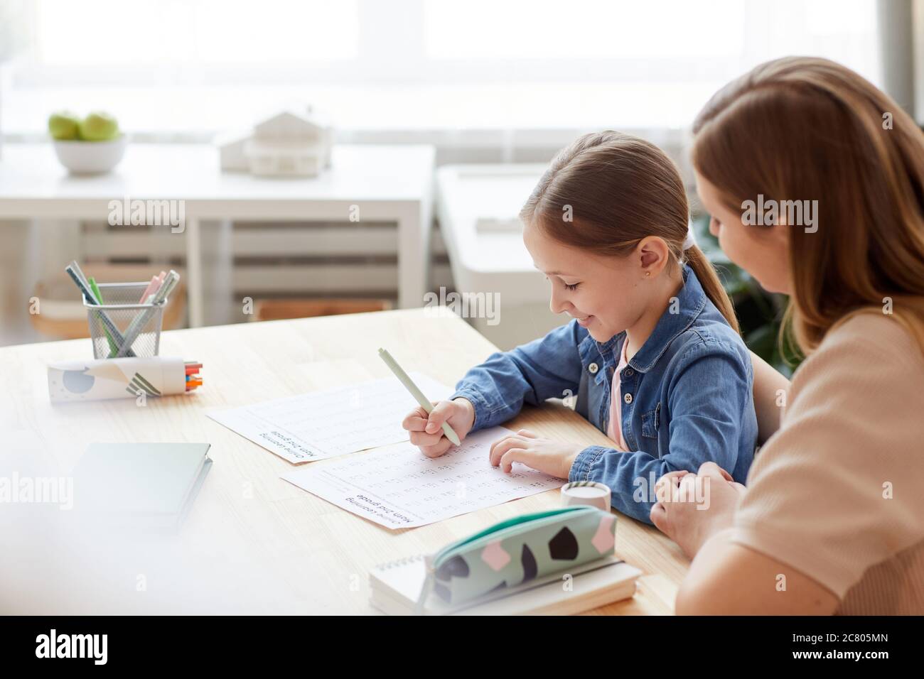 Portrait of smiling little girl doing math test for online school while ...