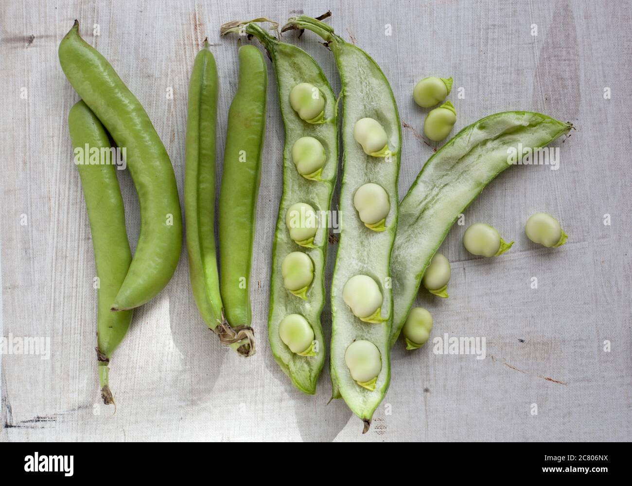 A close up of broad beans some open in their shells on a table top ...