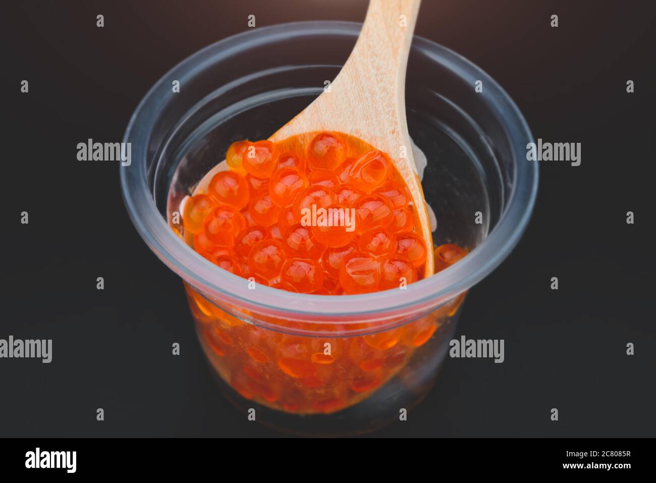 Salmon roe in wooden spoon with black background Stock Photo - Alamy