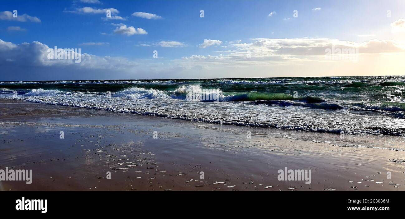 Wavy beach captured during the daytime with clouds in the sky Stock ...