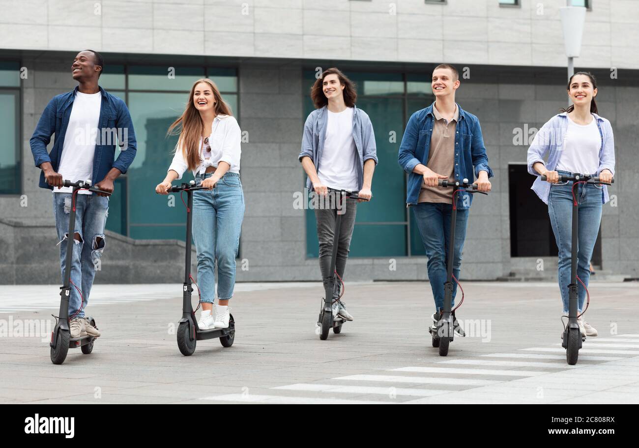 Five students having ride on motorized kick scooters Stock Photo - Alamy