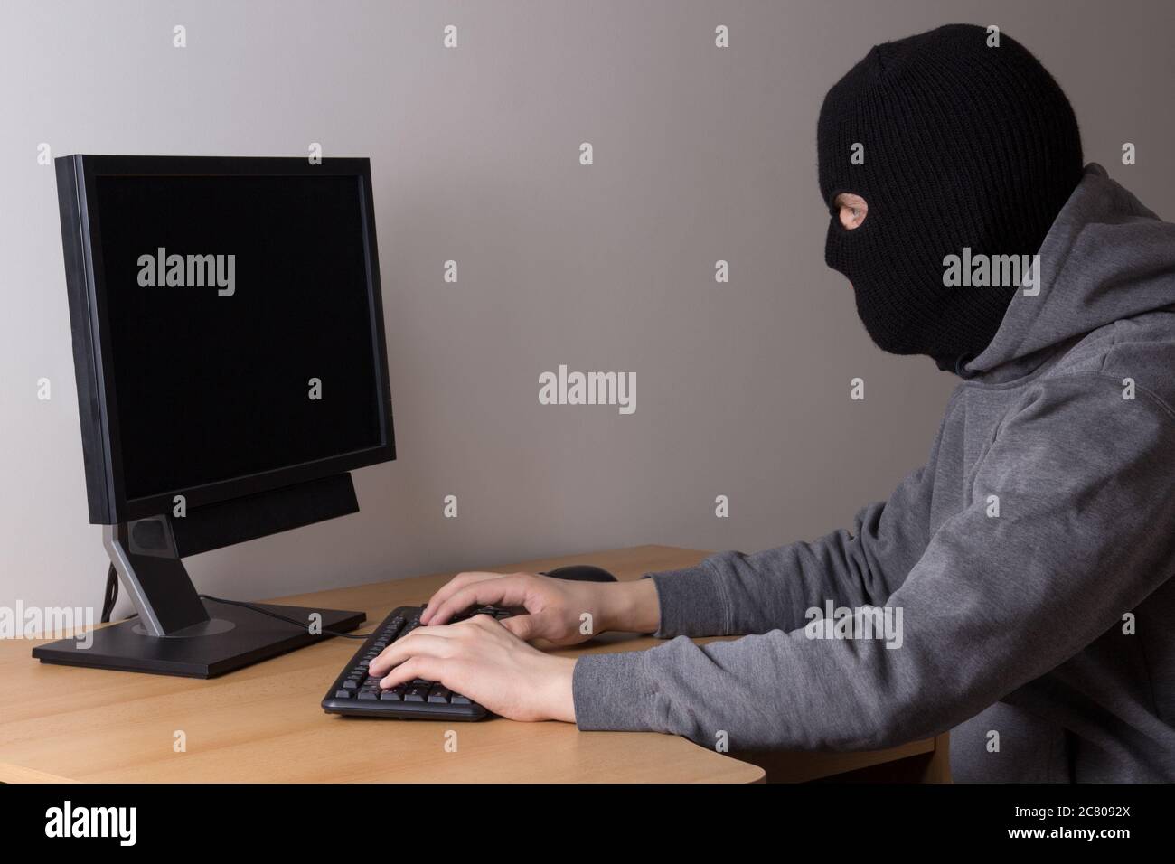 masked hacker with computer in office Stock Photo - Alamy