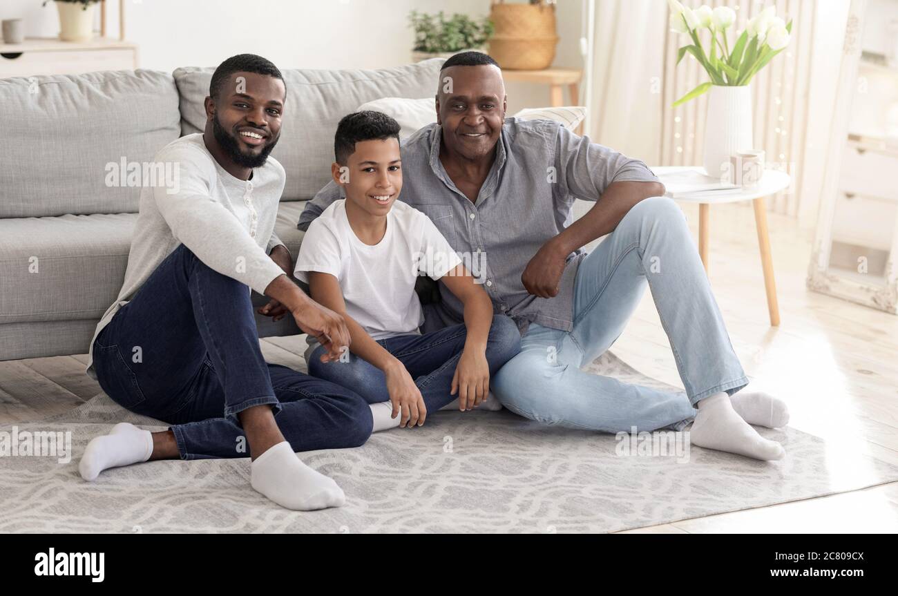 Happy black father, son and grandfather relaxing together on floor at ...