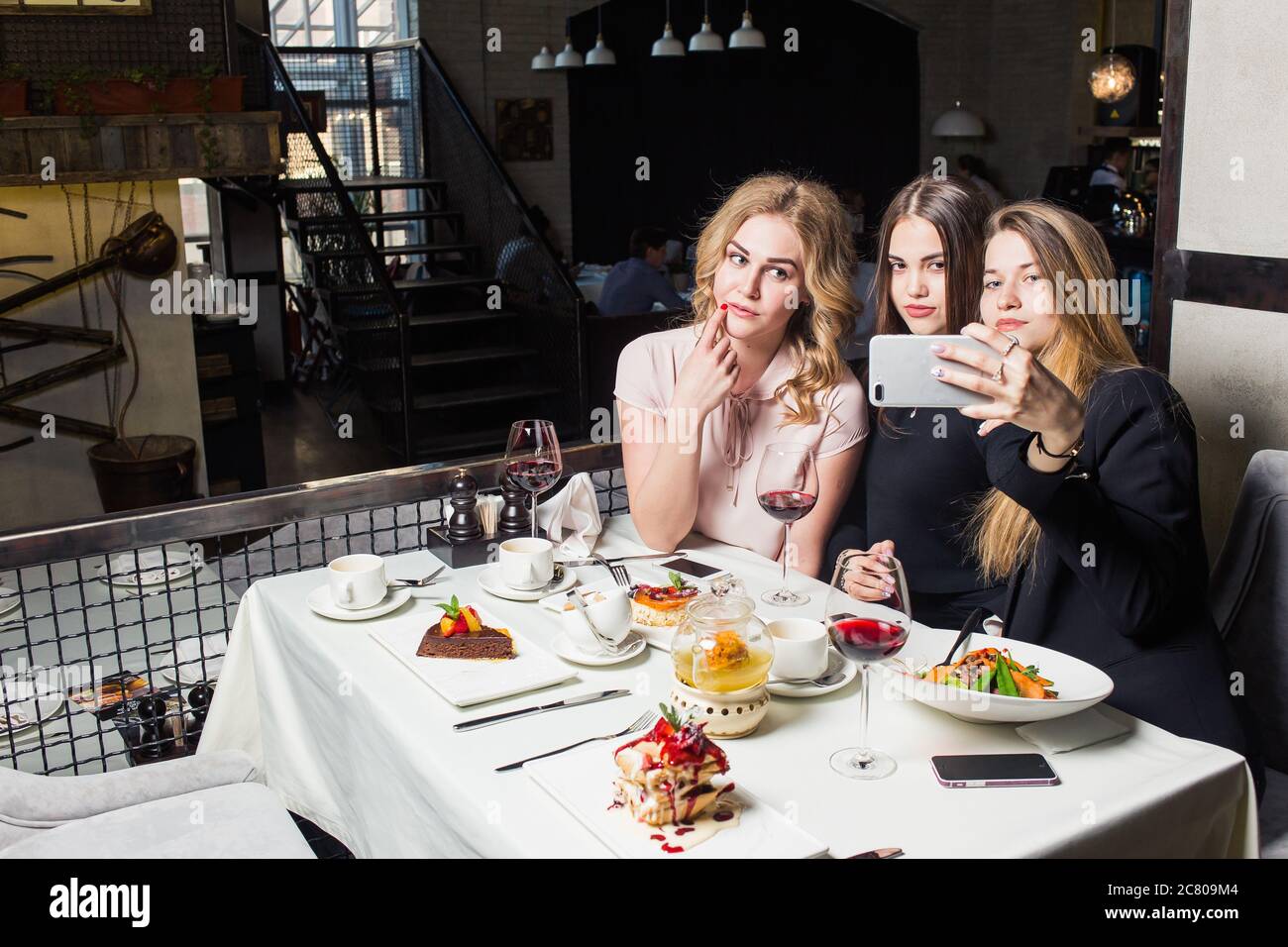 Three young girls are doing selfie in fast food restaurant Stock Photo ...