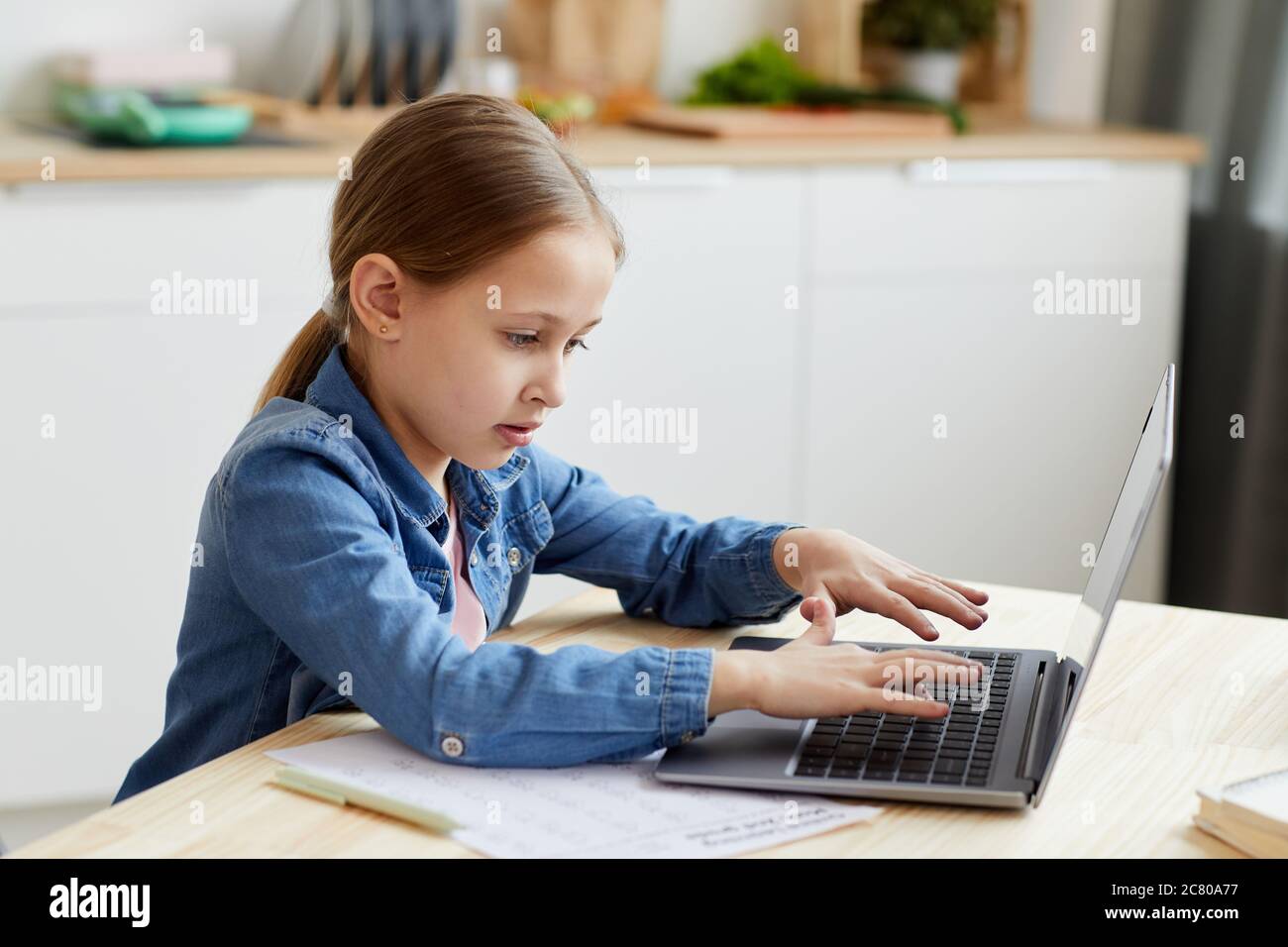 Side view portrait of cute blonde girl typing on laptop keyboard while ...