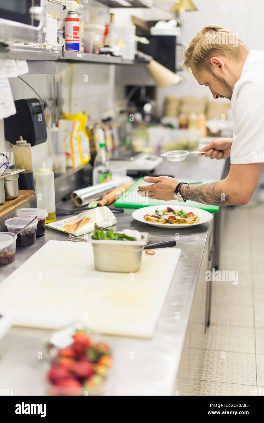 Chef in hotel or restaurant kitchen cooking, only hands. He is working ...