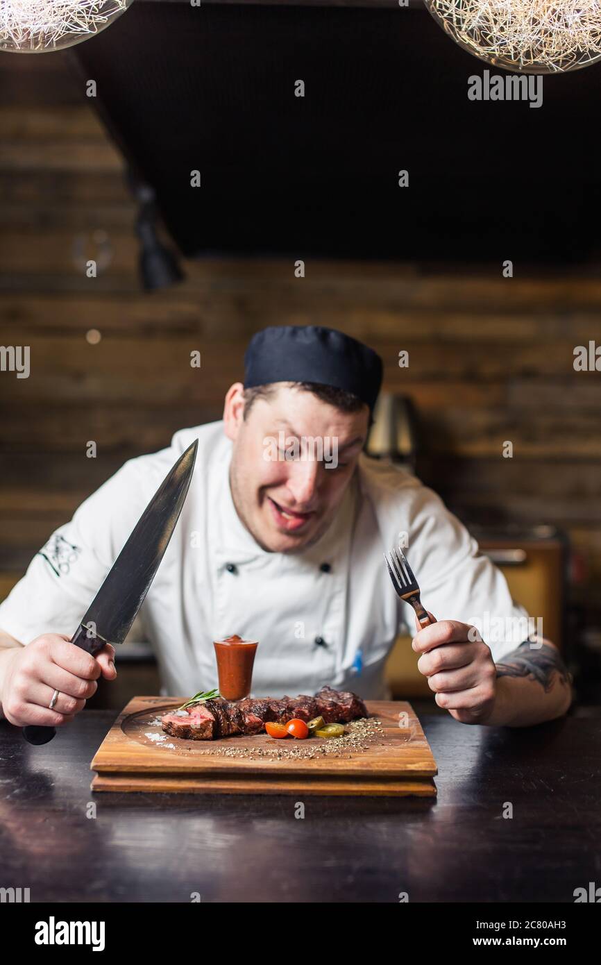 Chef leaning on the counter with a dish in a commercial kitchen Stock ...