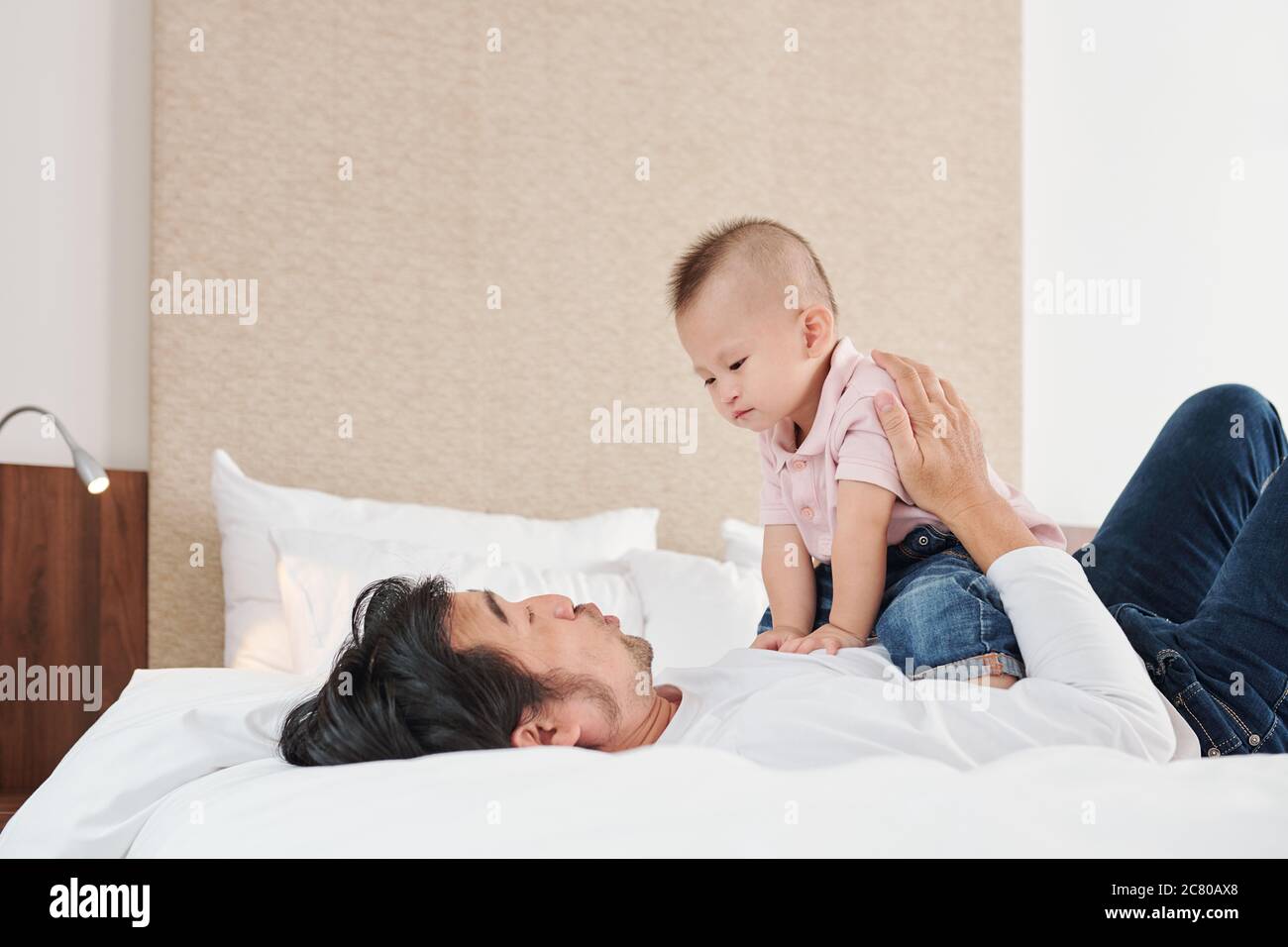 Happy young Vietnamese father with his one year old son playing at home ...