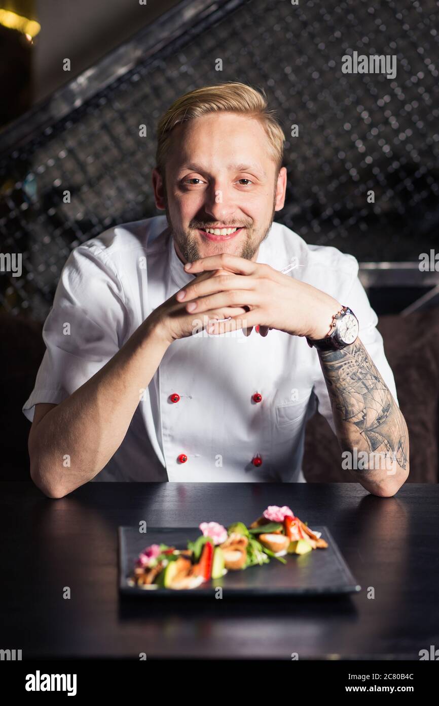 Chef leaning on the counter with a dish in a commercial kitchen Stock ...