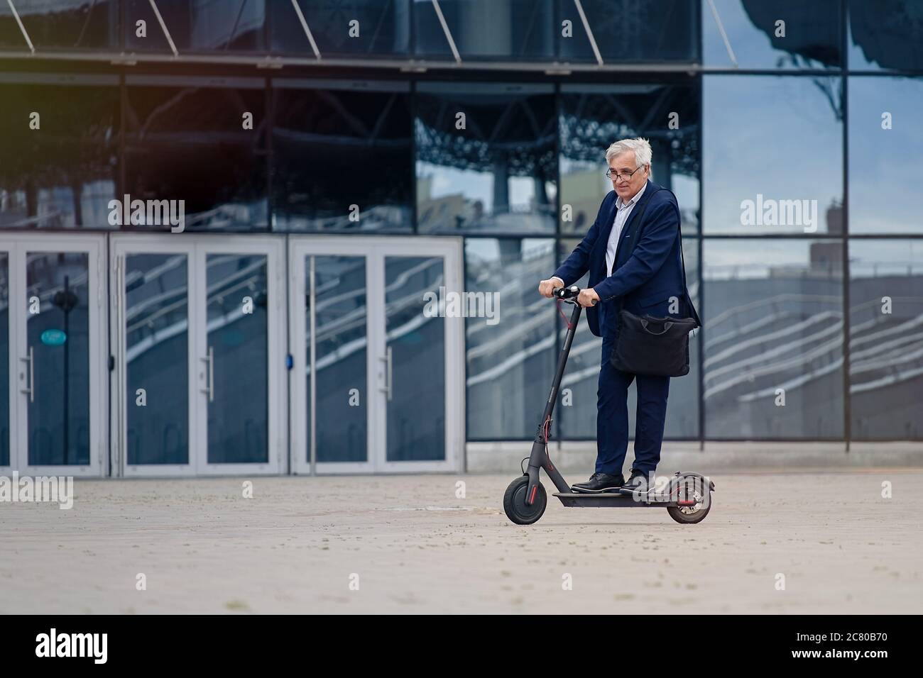 Senior businessman riding electric scooter in a cityscape Stock Photo ...