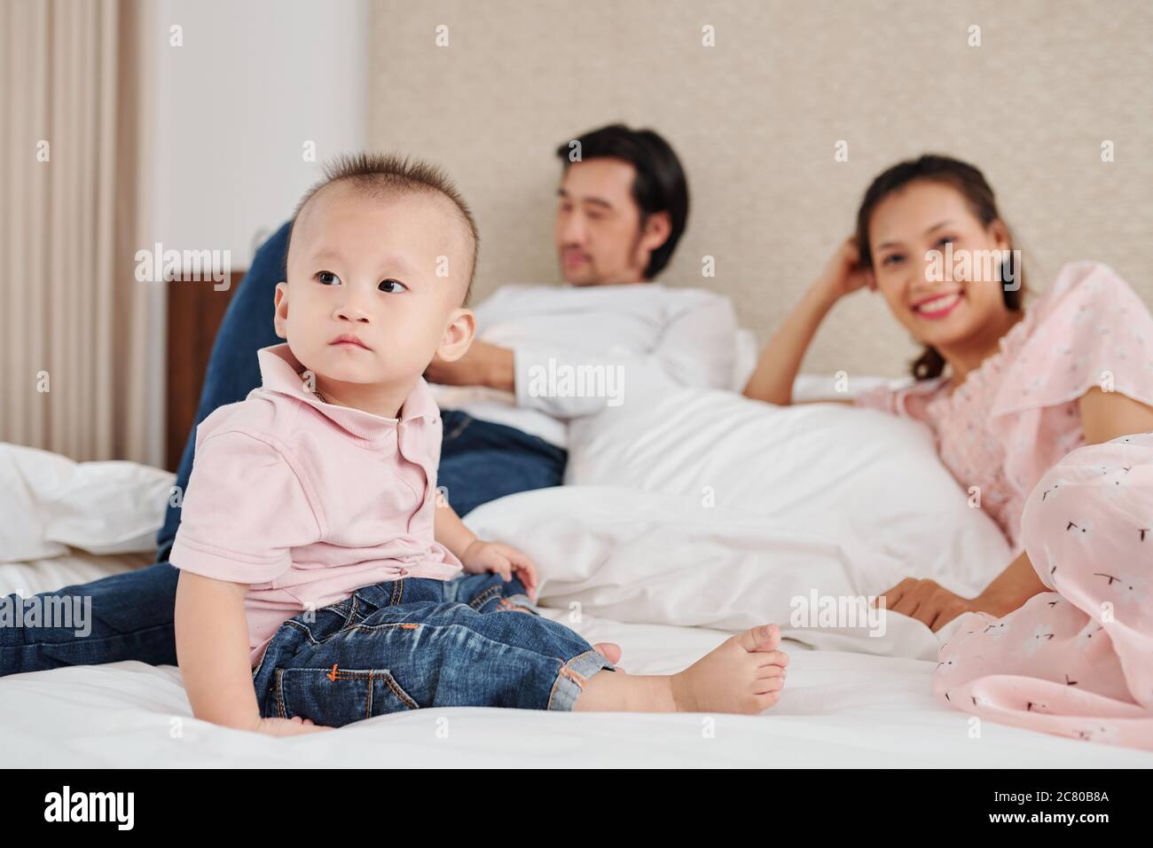 Adorable smiling little boy sitting and looking around when his parents ...