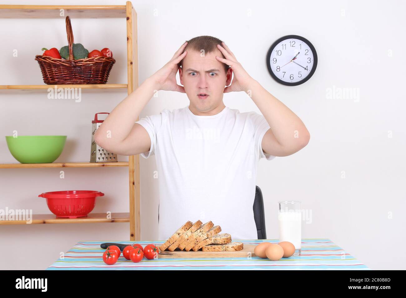 young shocked man sitting in the kitchen Stock Photo - Alamy