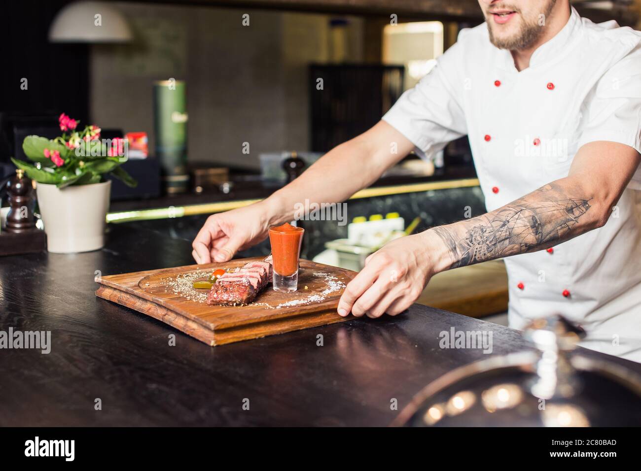 Chef leaning on the counter with a dish in a commercial kitchen Stock ...