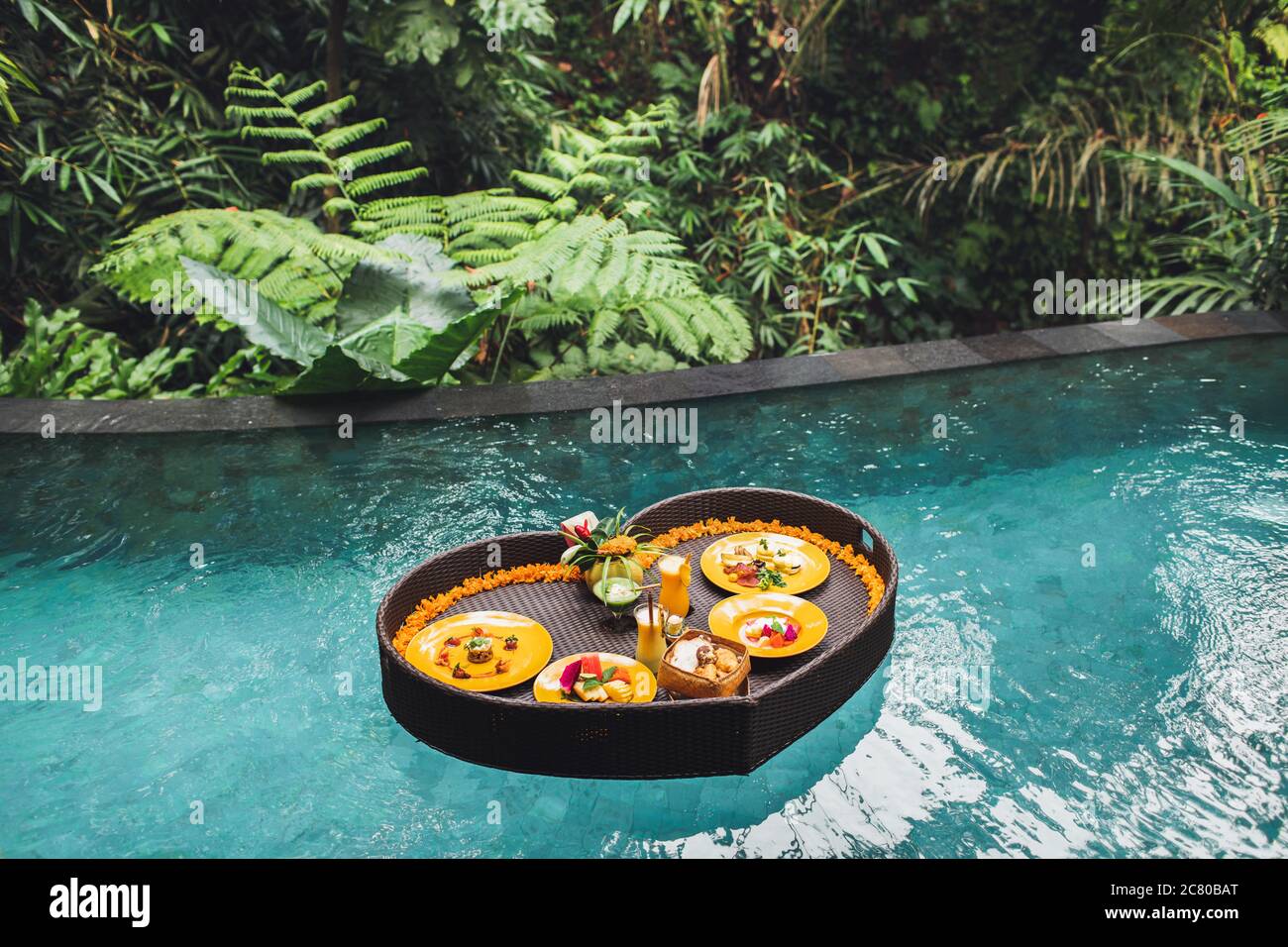 Floating breakfast in jungle swimming pool, tropical resort. Black ...