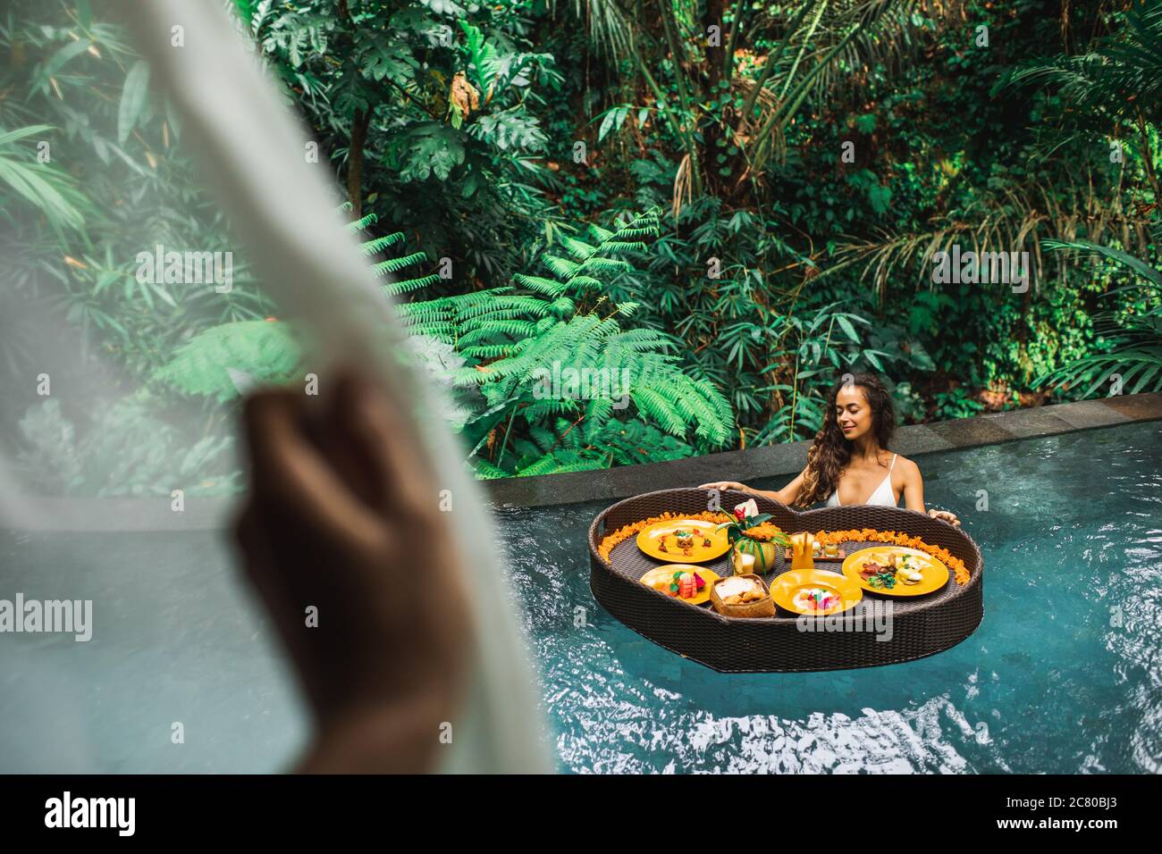 Girl relaxing and eating floating breakfast in jungle pool on luxury ...