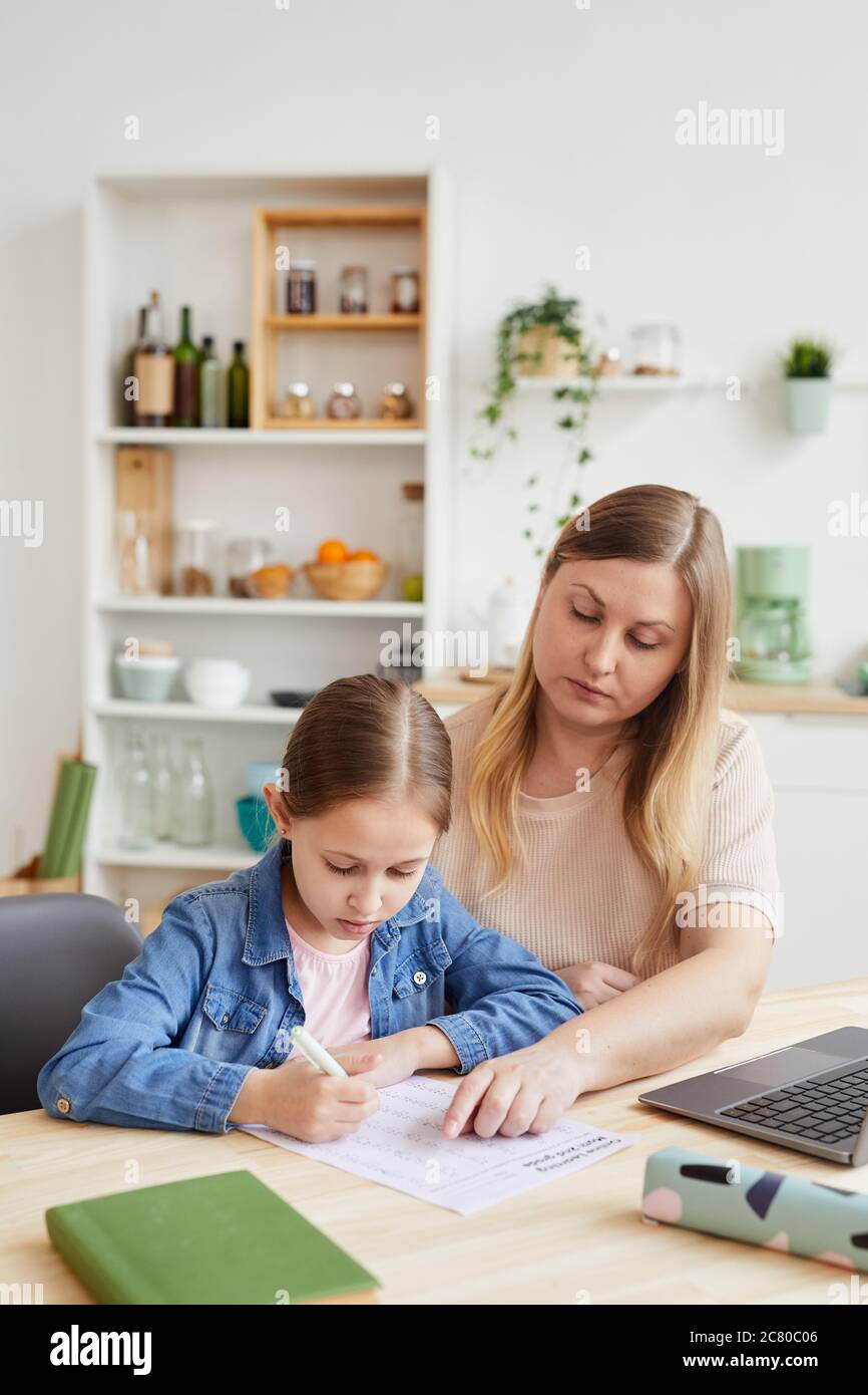 Vertical portrait of caring adult woman helping girl doing homework or ...
