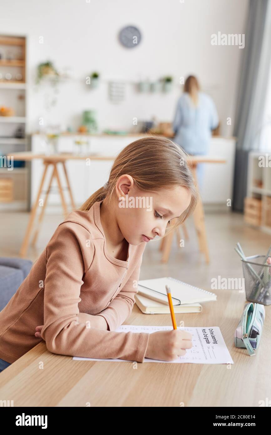 Vertical side view portrait of cute girl doing homework for elementary ...