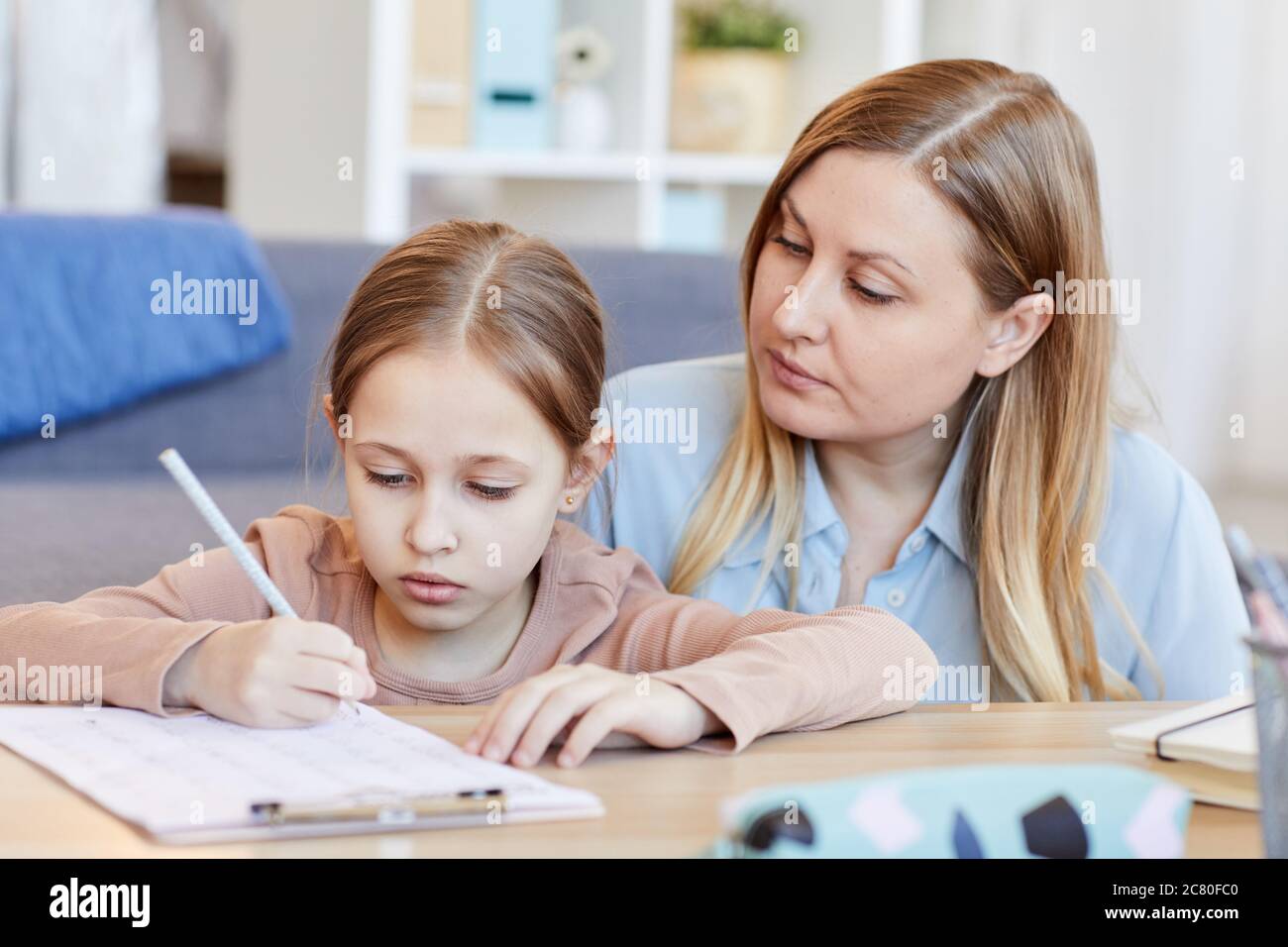 Portrait of loving adult mother looking at cute little girl doing ...