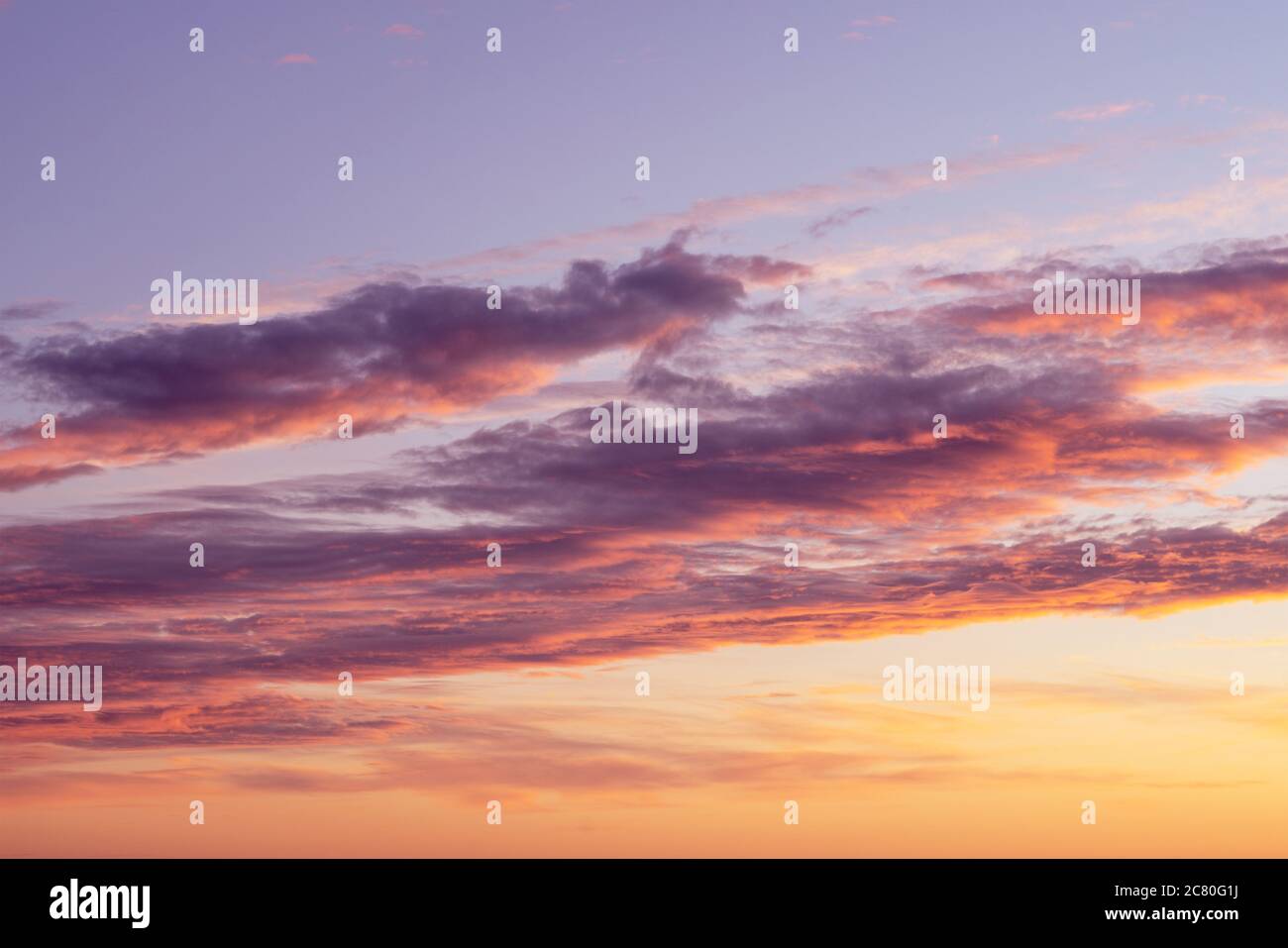 Cloudy sunset in orange and violet colors in the late summer afternoon ...