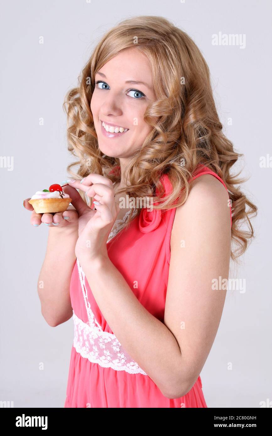 Happy blonde woman with little cake in hand Stock Photo - Alamy