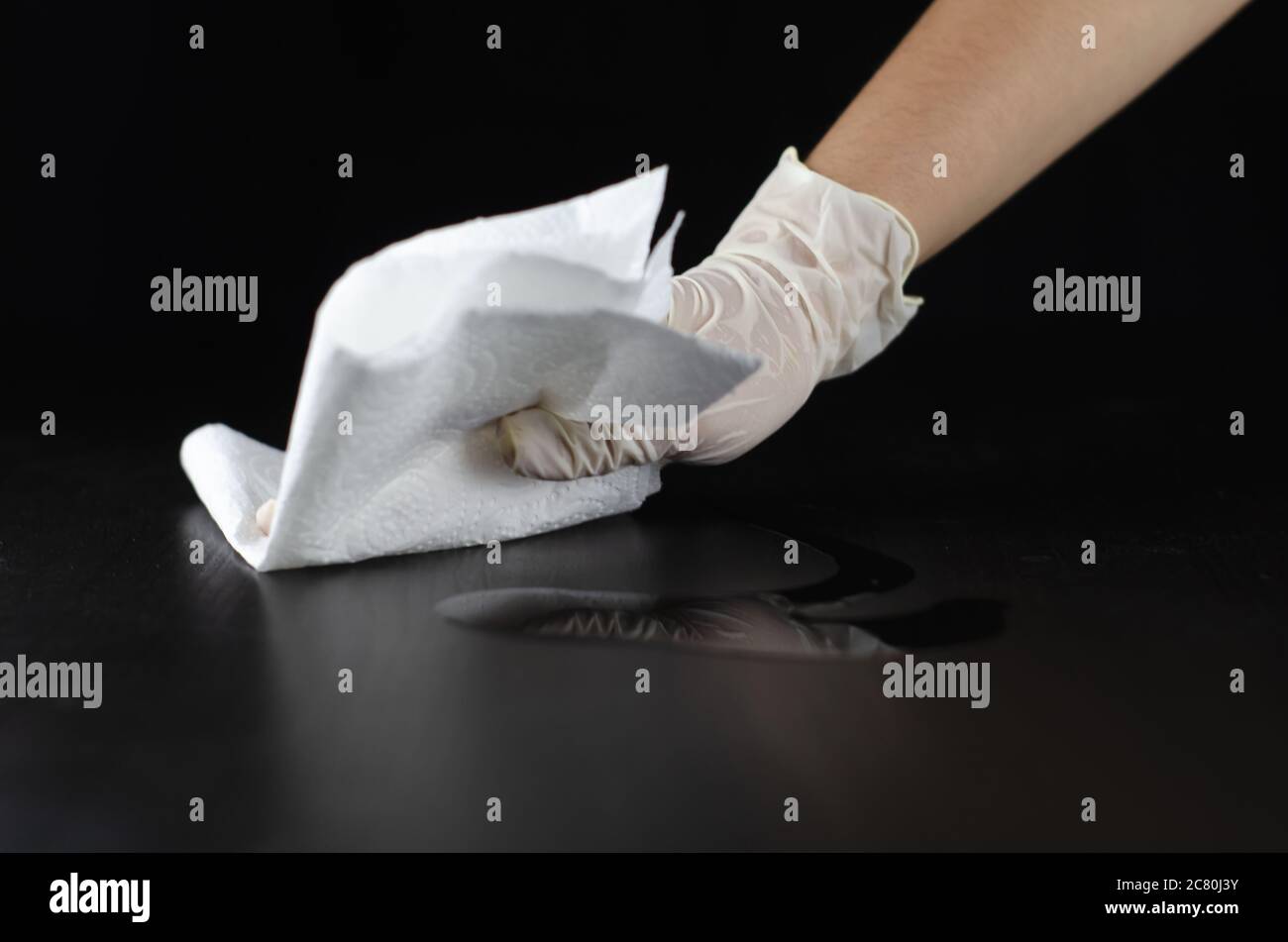 Closeup shot of a hand wearing a glove wiping a liquid spill on the ...